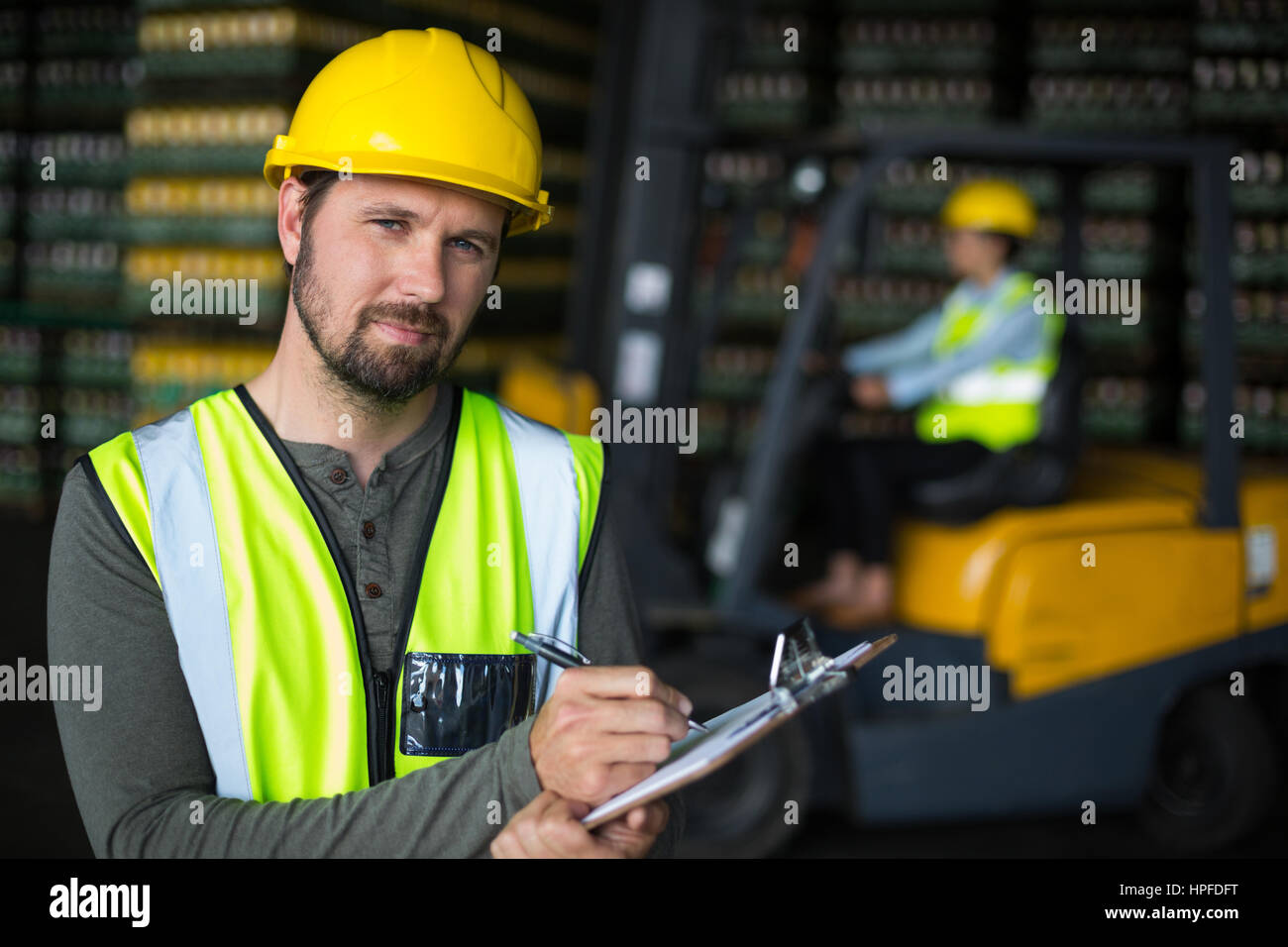 Portrait of factory worker holding clipboard in drinks production ...