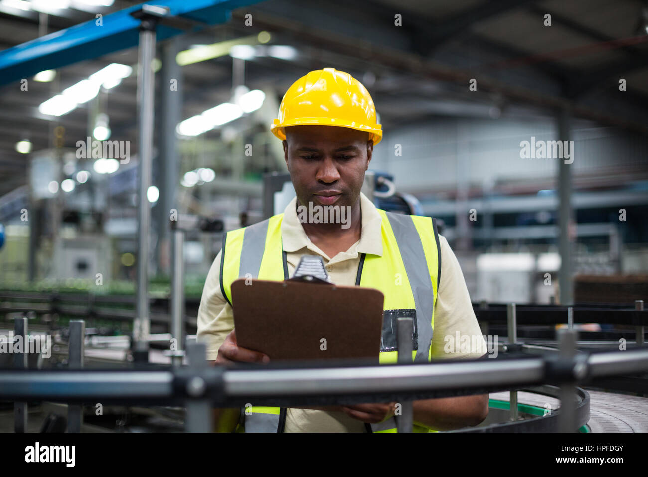 Thoughtful factory worker looking at clipboard in factory Stock Photo ...