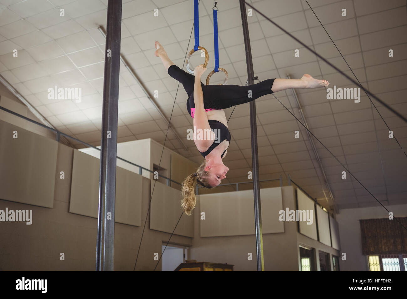 Female gymnast practicing gymnastics on rings in gymnasium Stock Photo ...