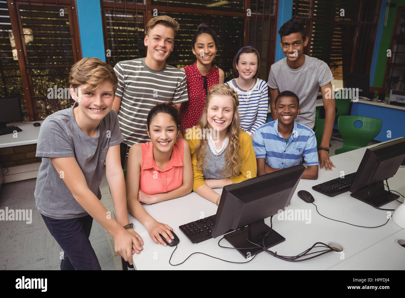 Portrait of smiling students studying in computer classroom at school ...