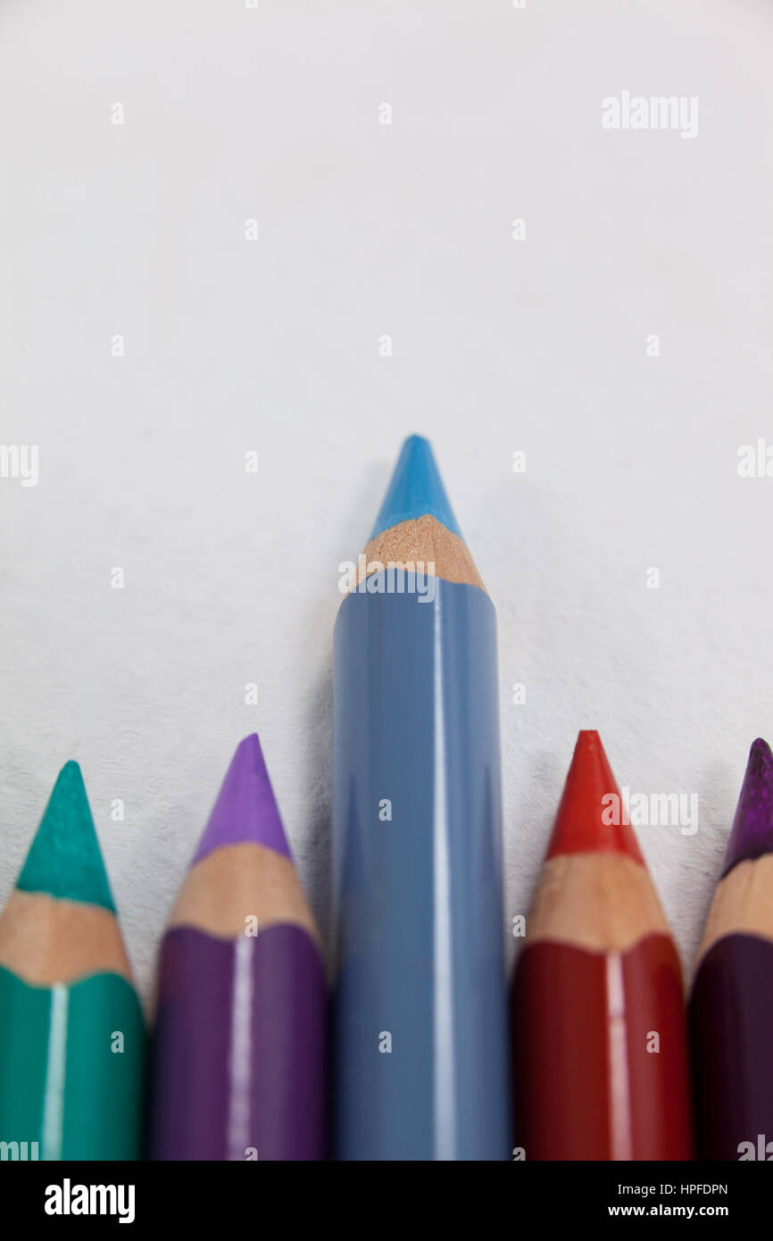Blue pencil standing out from a row of colored pencils on white ...