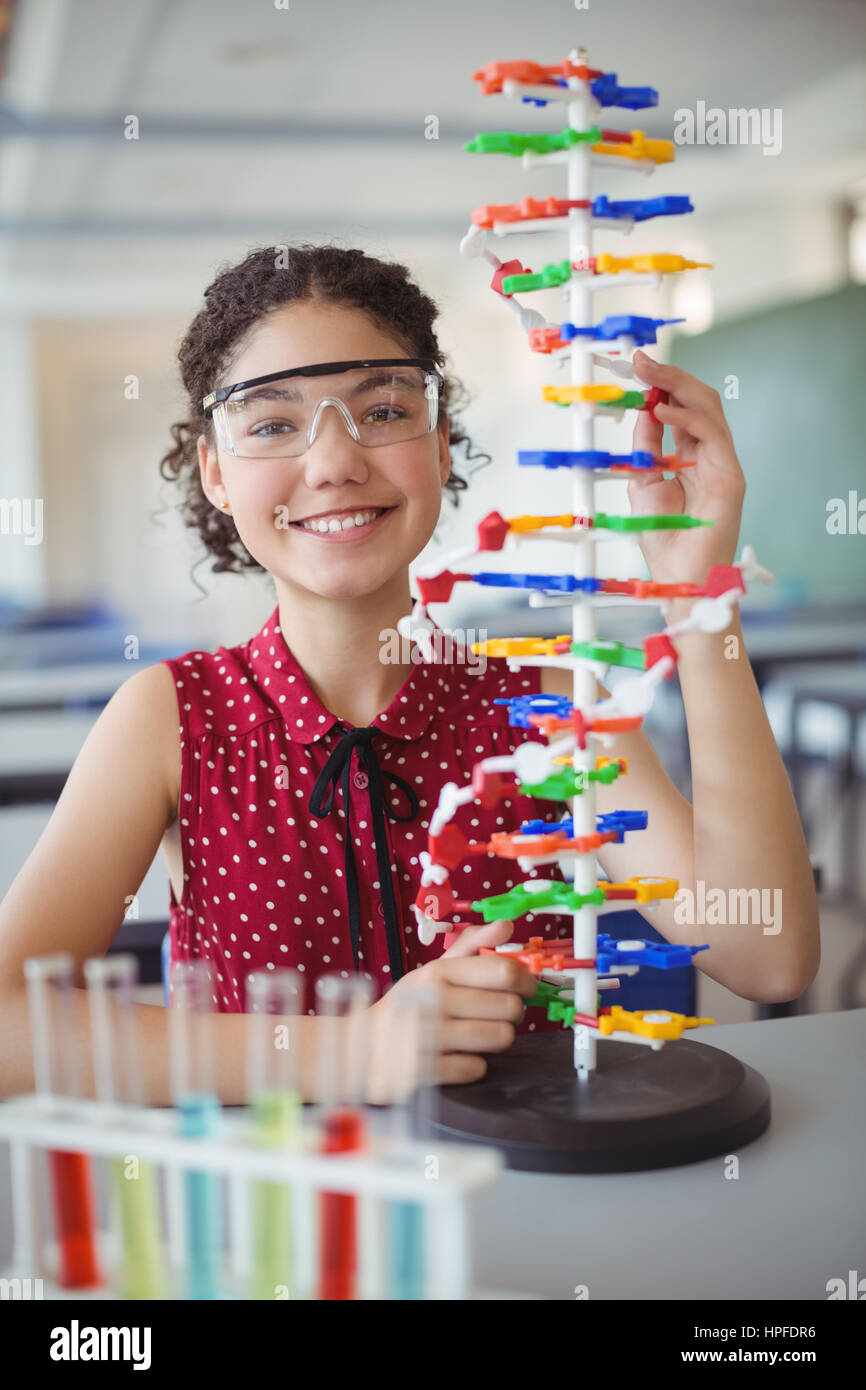 Portrait of happy schoolgirl experimenting molecule model in laboratory ...