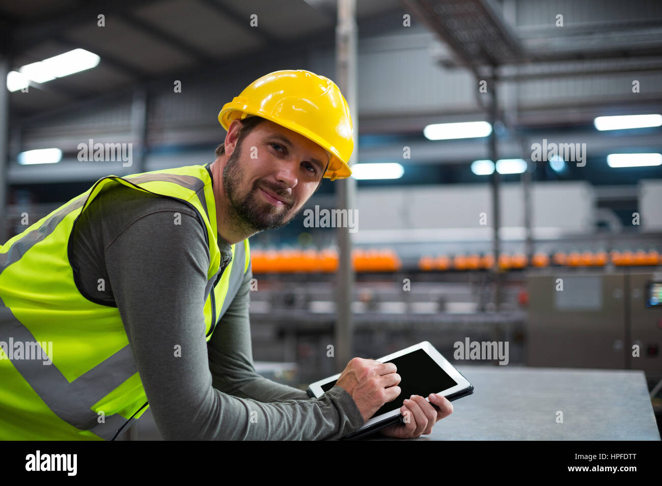 Portrait of factory worker using digital tablet at drinks production ...