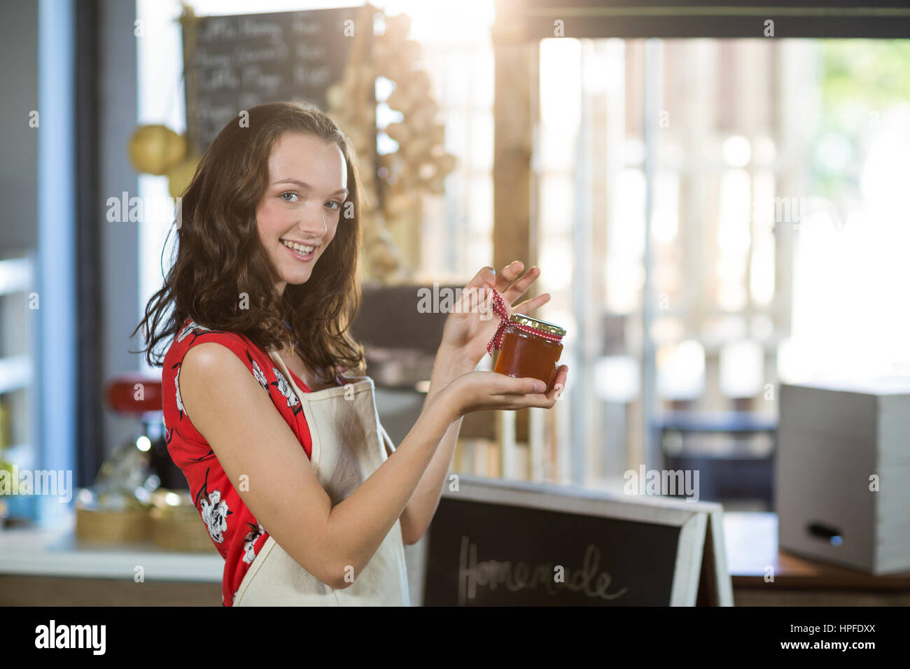 Portrait of a female shop assistant holding a jar of jam Stock Photo ...