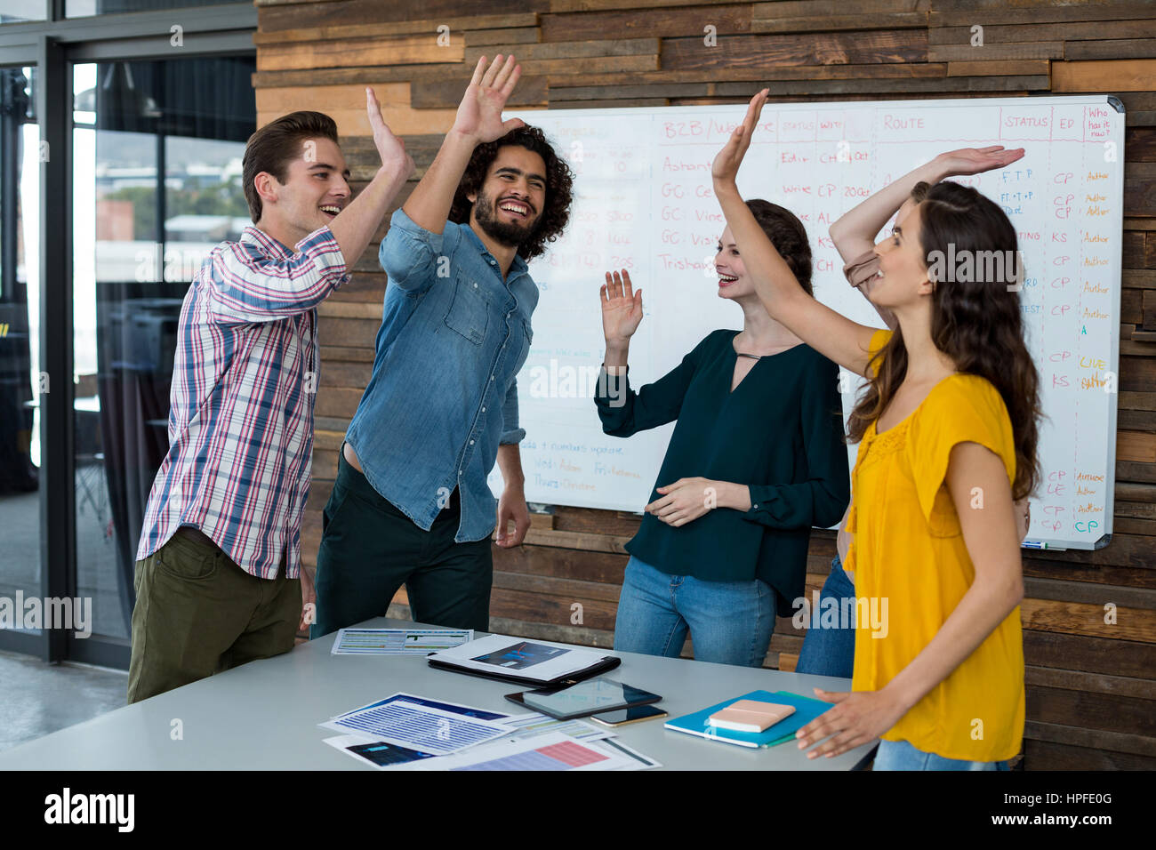 Happy business executives giving high five in office Stock Photo - Alamy