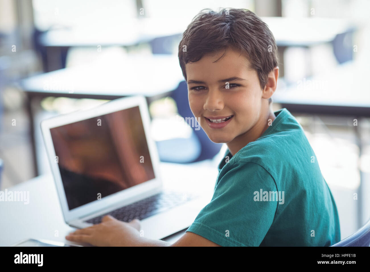 Portrait of schoolboy using laptop in classroom at school Stock Photo ...