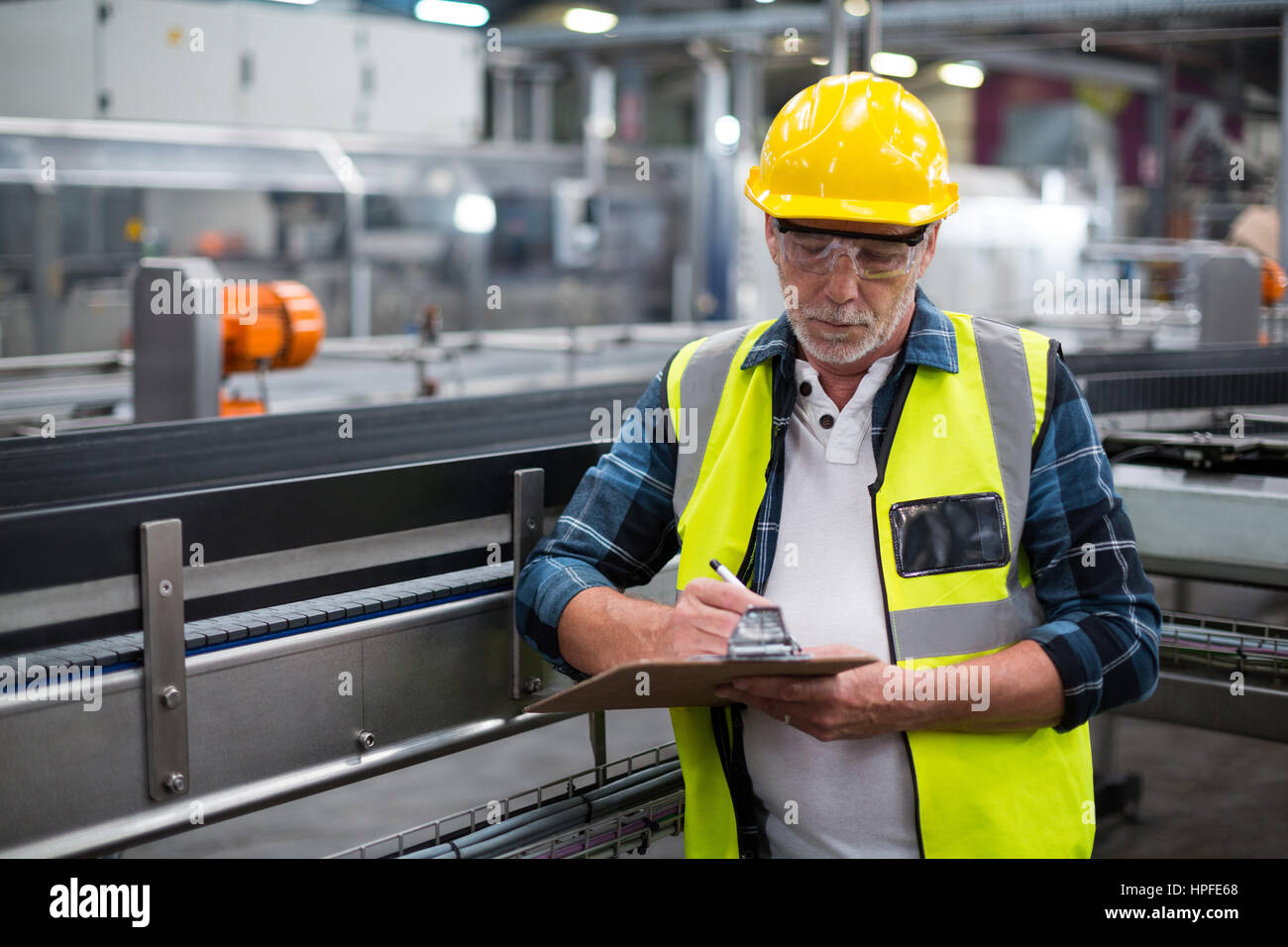 Male factory worker maintaining record on clipboard in drinks ...