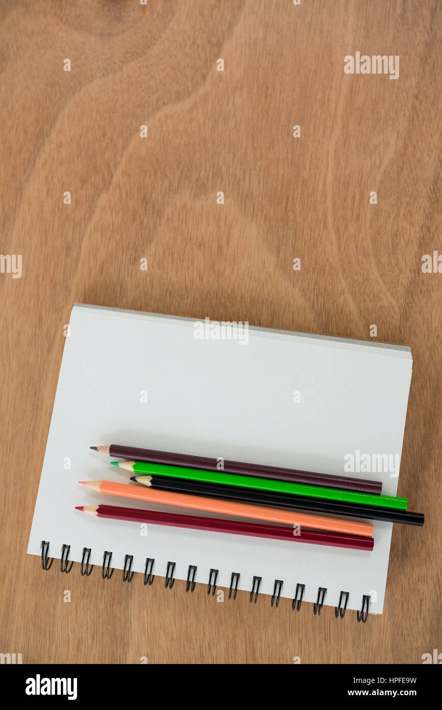 Colored pencils kept on the book on wooden background Stock Photo - Alamy