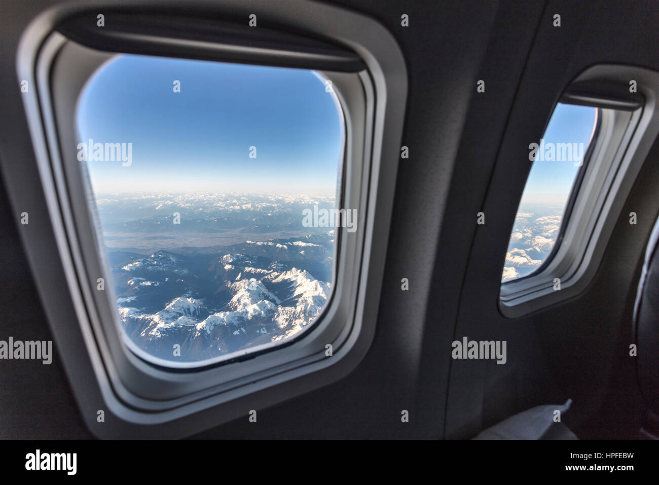 The view out of two airplane windows over snow-covered mountains Stock ...