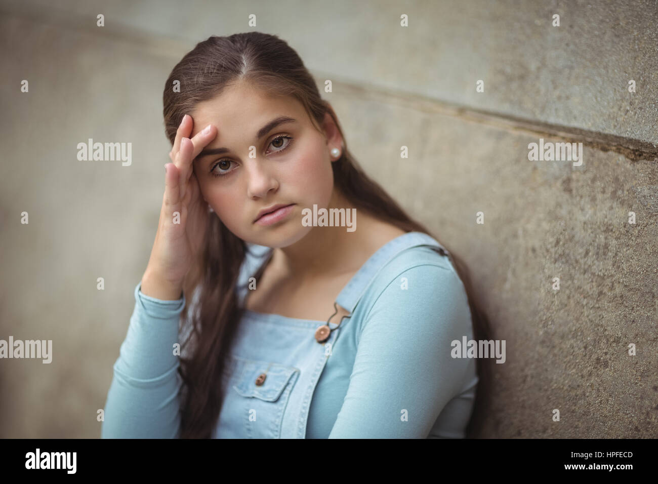 Portrait of anxious teenage girl leaning on wall at school Stock Photo ...