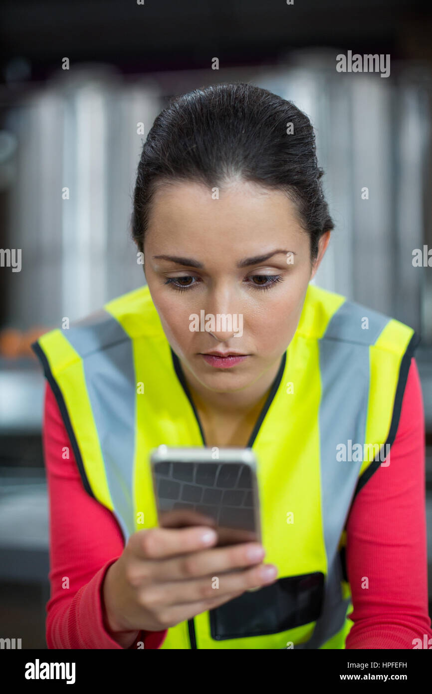 Female factory worker using mobile phone at drinks production factory ...