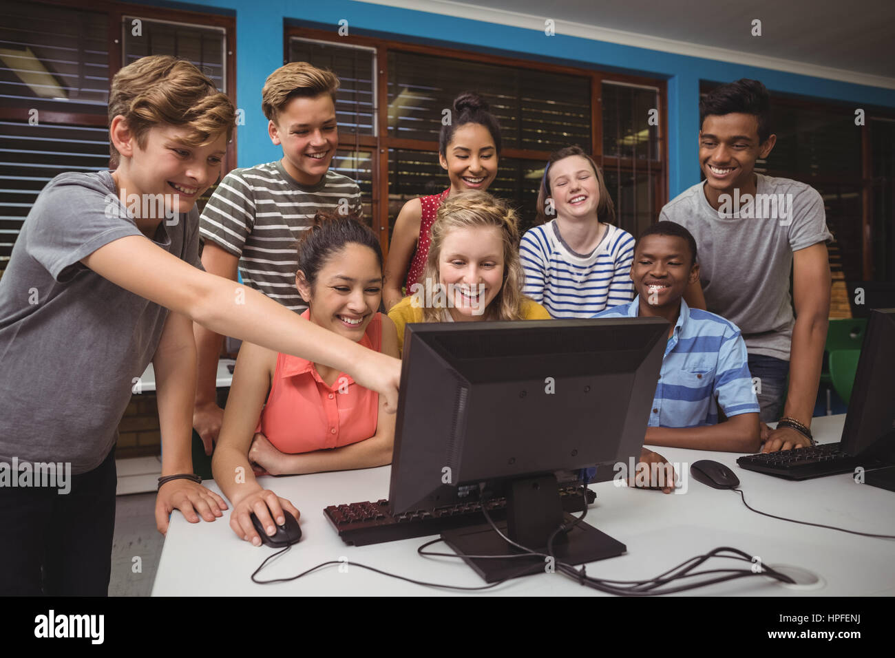 Smiling students studying together in computer classroom at school ...