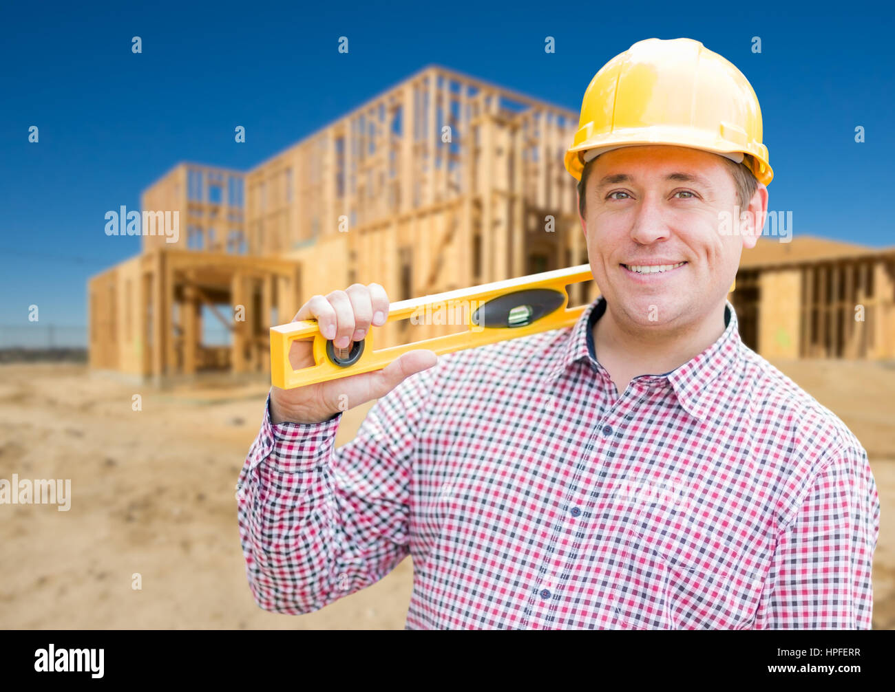Smiling Male Contractor in Hardhat Holding Level at Home Construction ...
