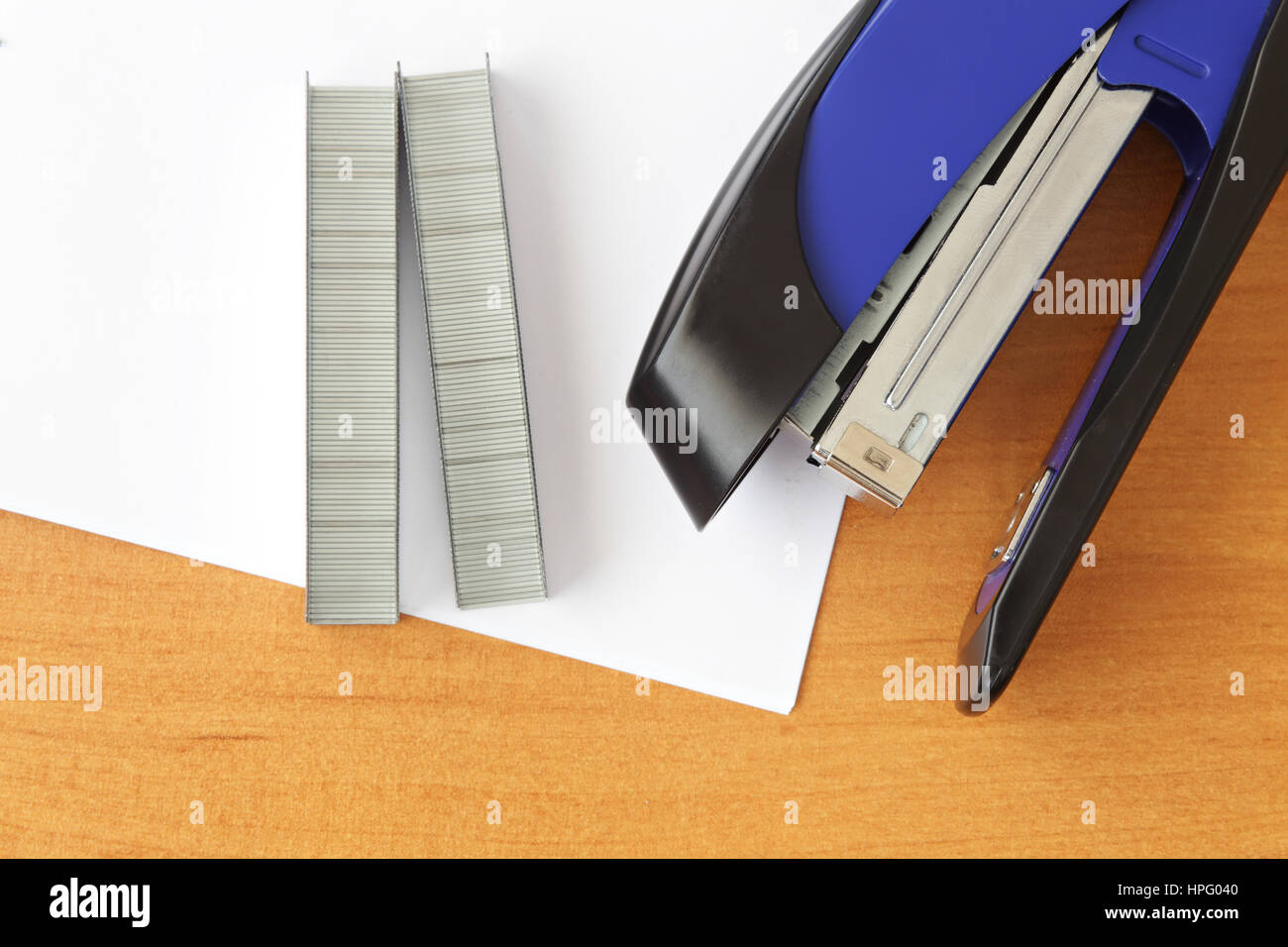 Blue stapler and staples with paper on wood table Stock Photo - Alamy