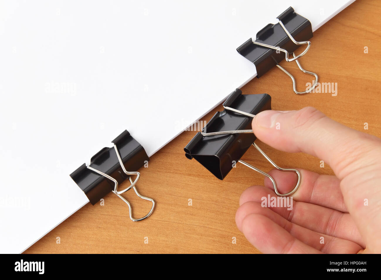 Hand holding paper clip next to white paper Stock Photo - Alamy