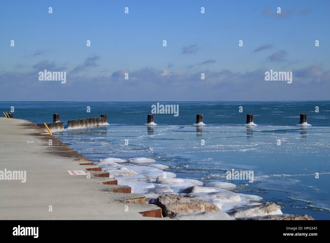 View of wooden posts reflected onto the ice of a frozen and icy Lake ...