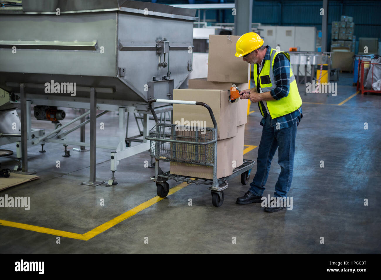 Factory worker loading cardboard boxes in drinks production factory ...