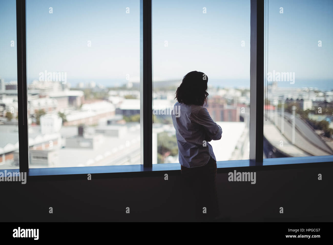 Female executive looking through window in office Stock Photo - Alamy