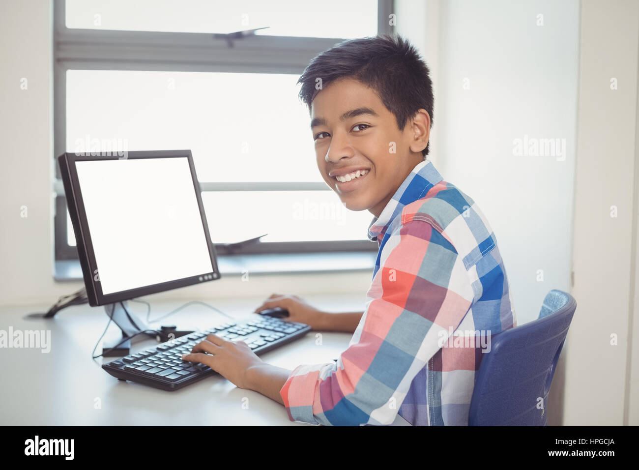 Portrait of smiling schoolboy using computer at school Stock Photo - Alamy