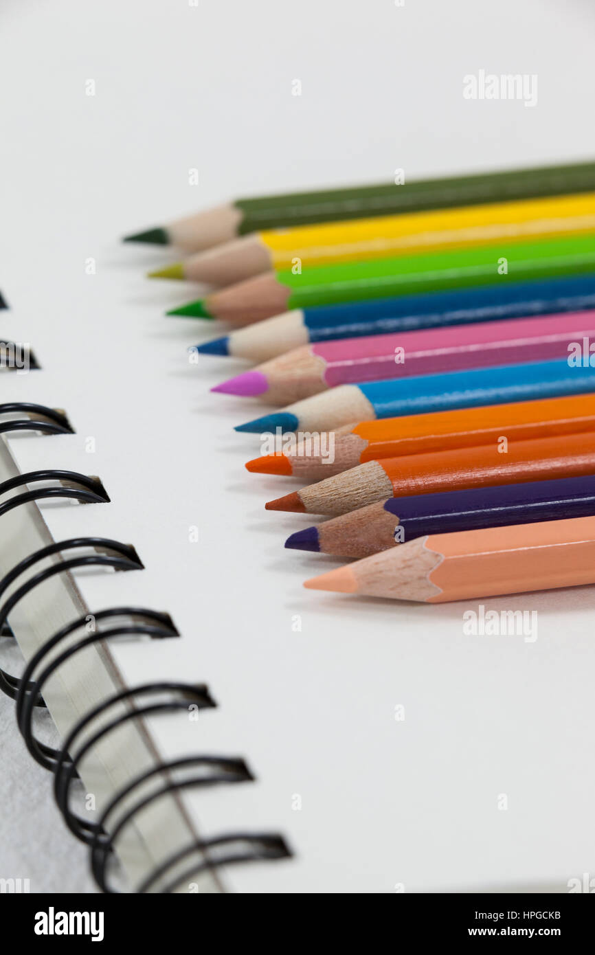 Close-up of colored pencils and notebook on white background Stock ...