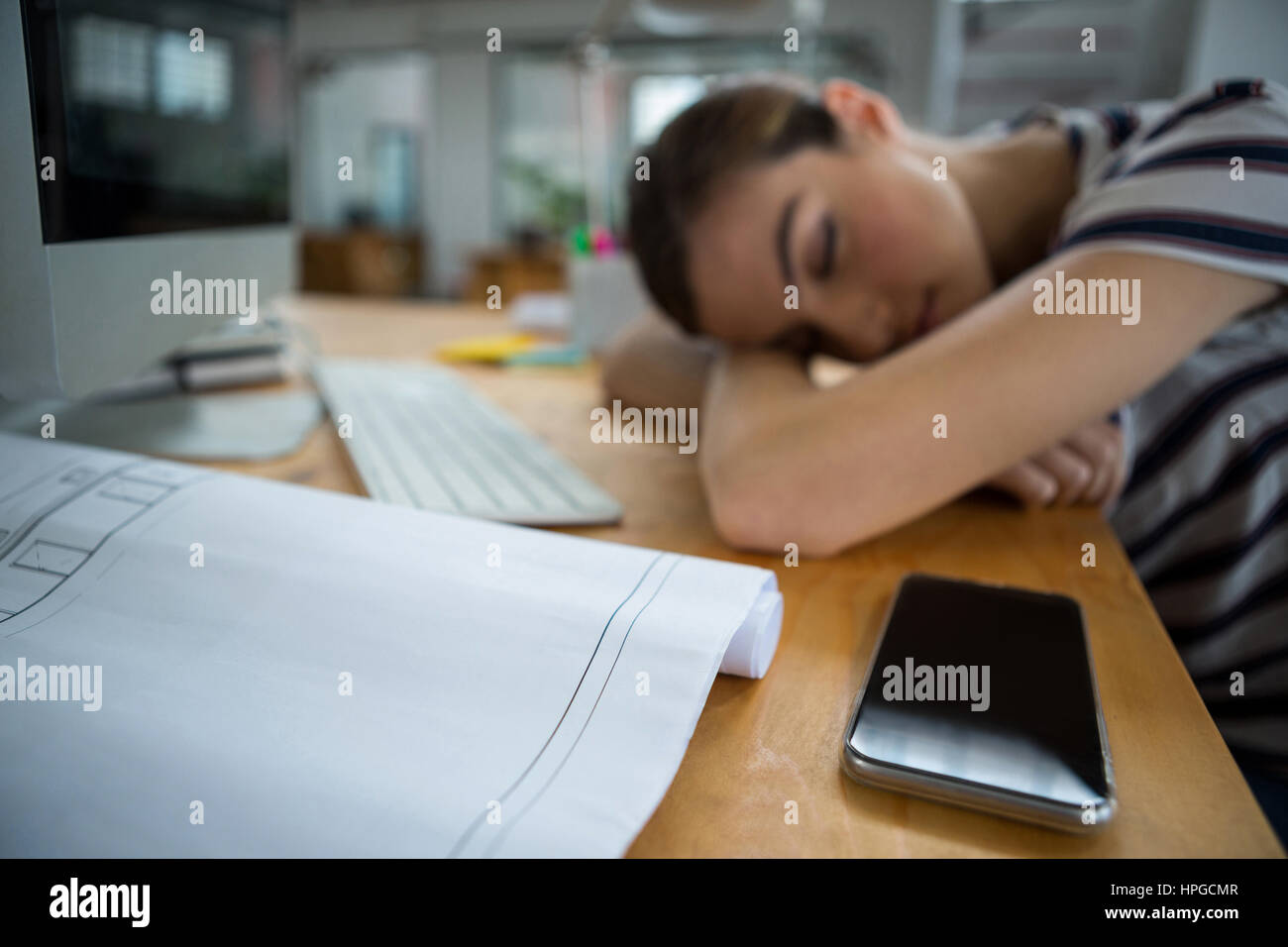 Overworked graphic designer sleeping on his desk in the creative office ...