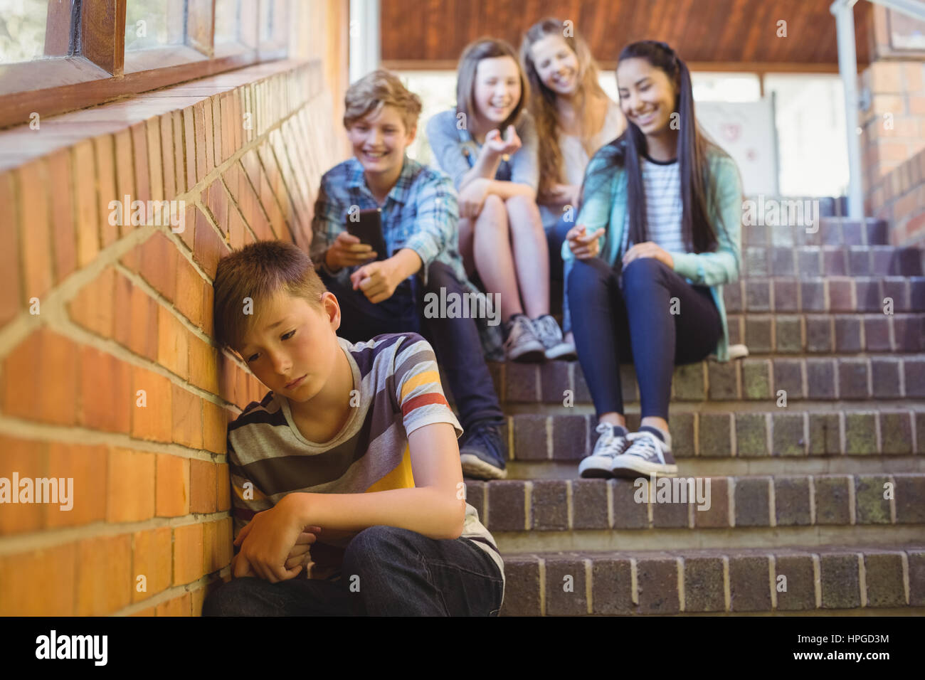 School friends bullying a sad boy in school corridor at school Stock ...