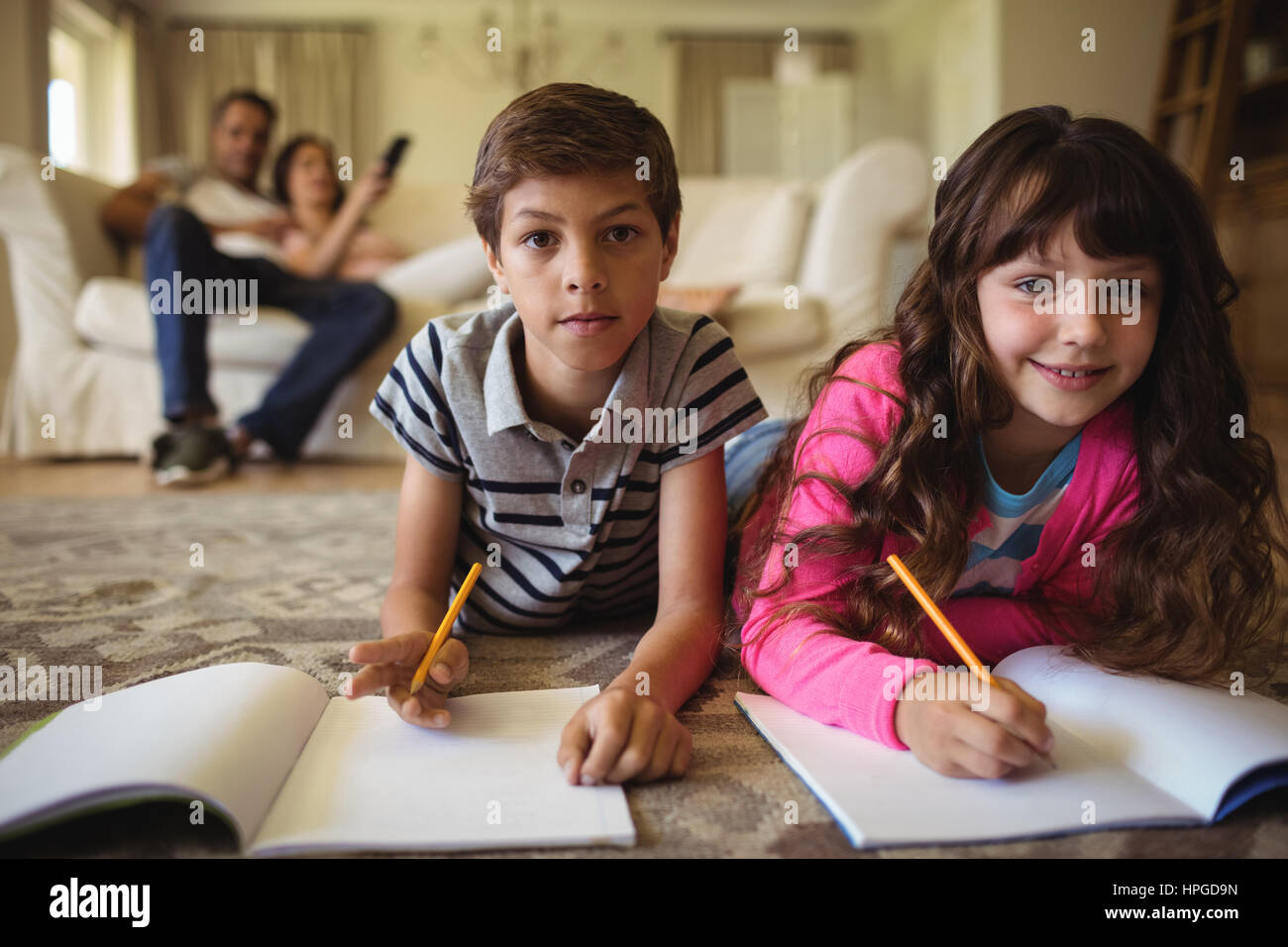 Portrait of kids doing homework while lying on rug at home Stock Photo ...