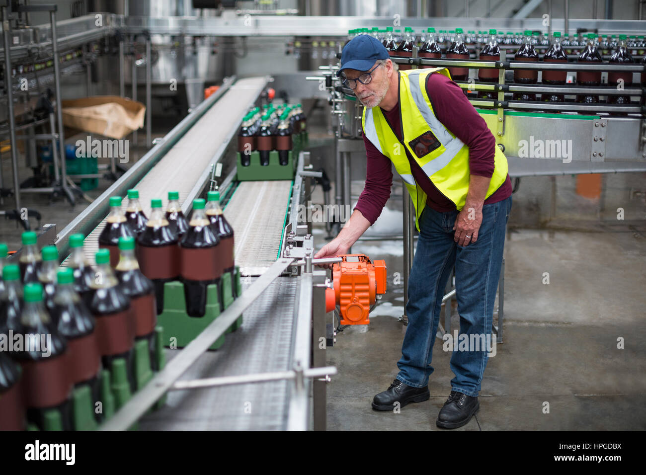 Male factory worker inspecting production line at drinks production ...
