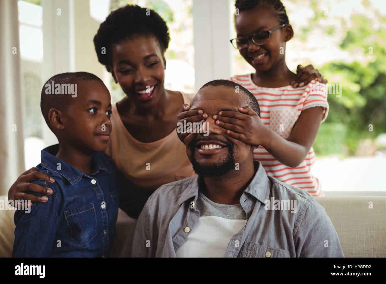Family covering man eyes for surprise a home Stock Photo - Alamy