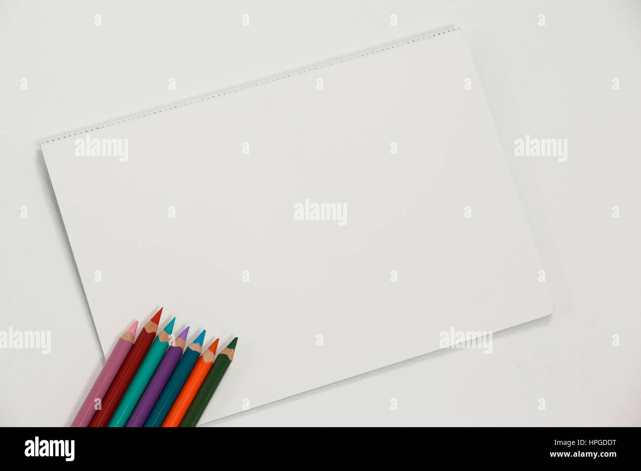 Colored pencils and notebook on white background Stock Photo - Alamy