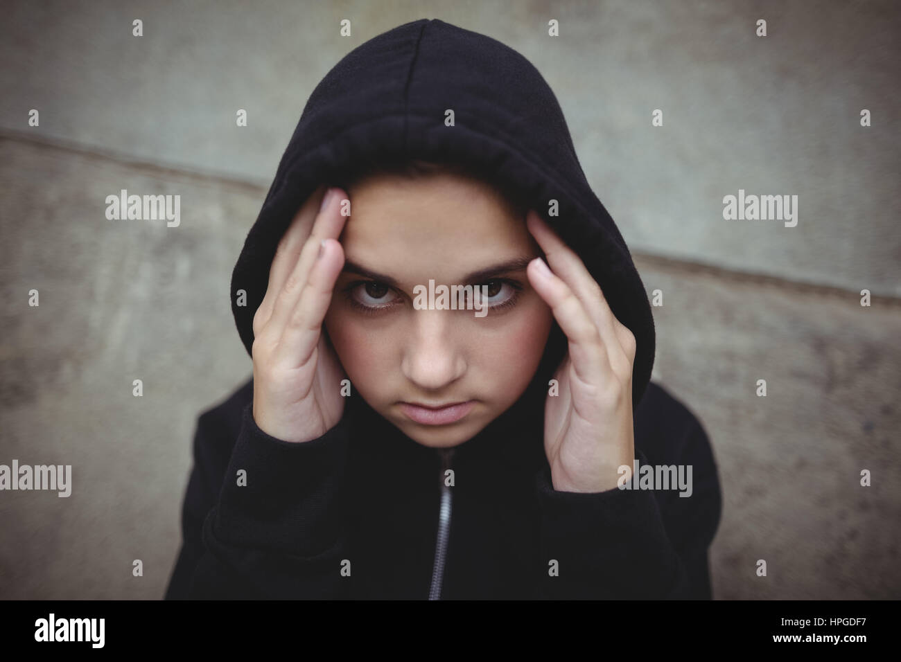 Close-up of anxious teenage girl in black hooded jacket looking at ...