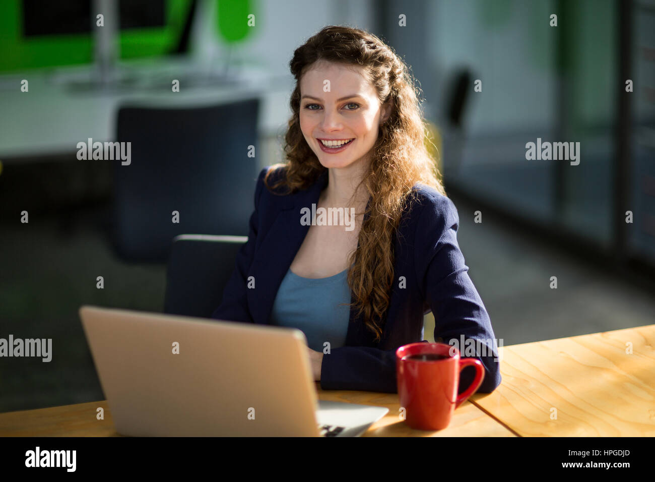 Portrait of smiling female business executive sitting at desk with ...