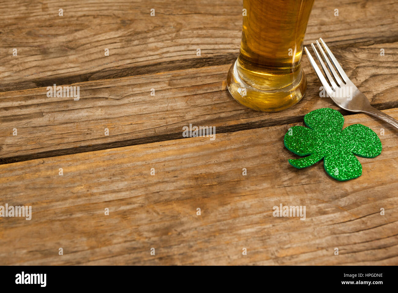Glass of beer, fork and shamrock for St Patricks Day against wooden ...