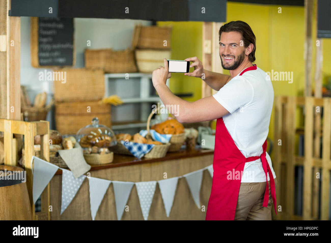 Portrait of bakery staff photographing bakery snacks and bread on the ...