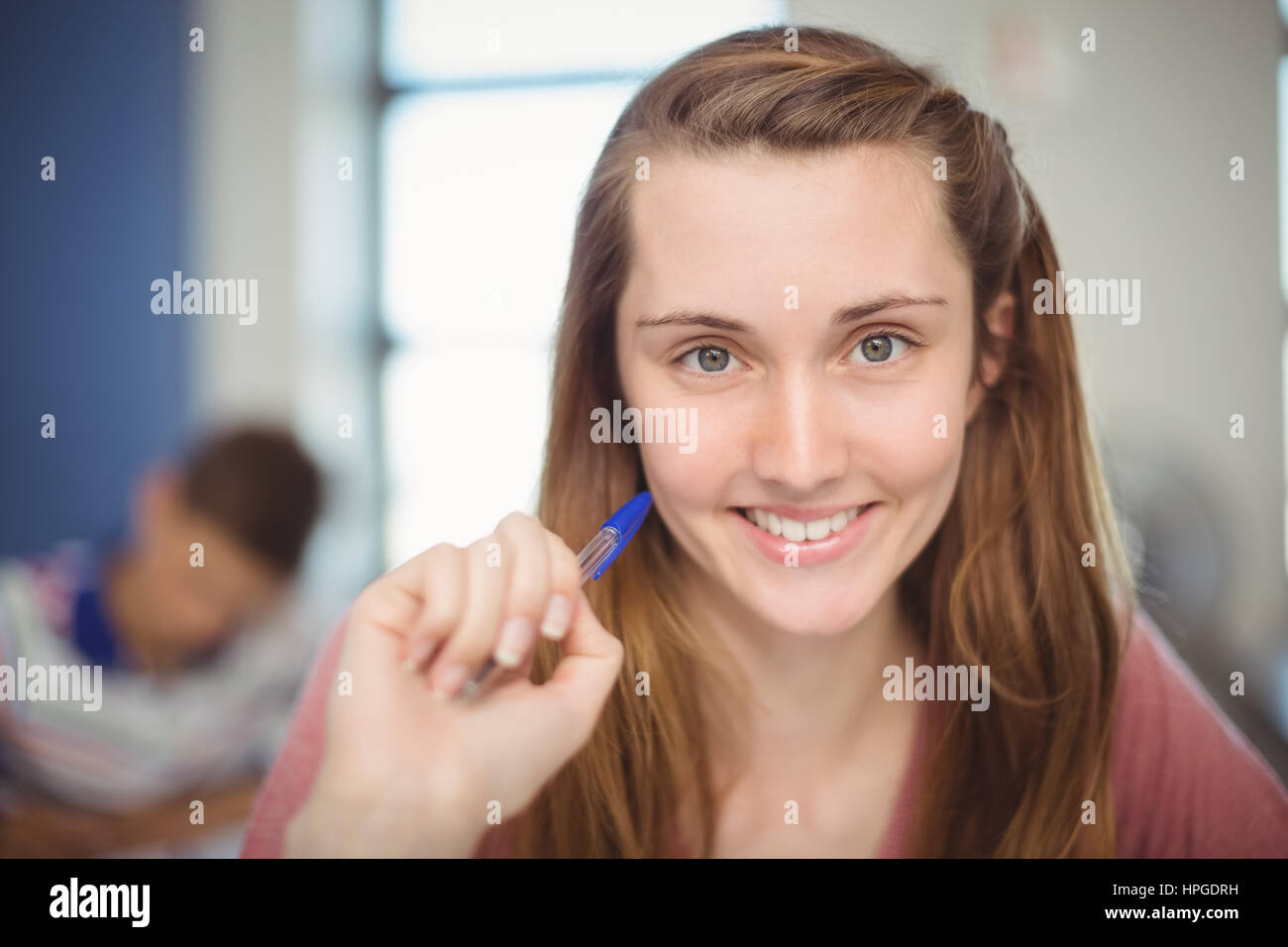 Portrait of smiling school girl doing homework in classroom at school ...