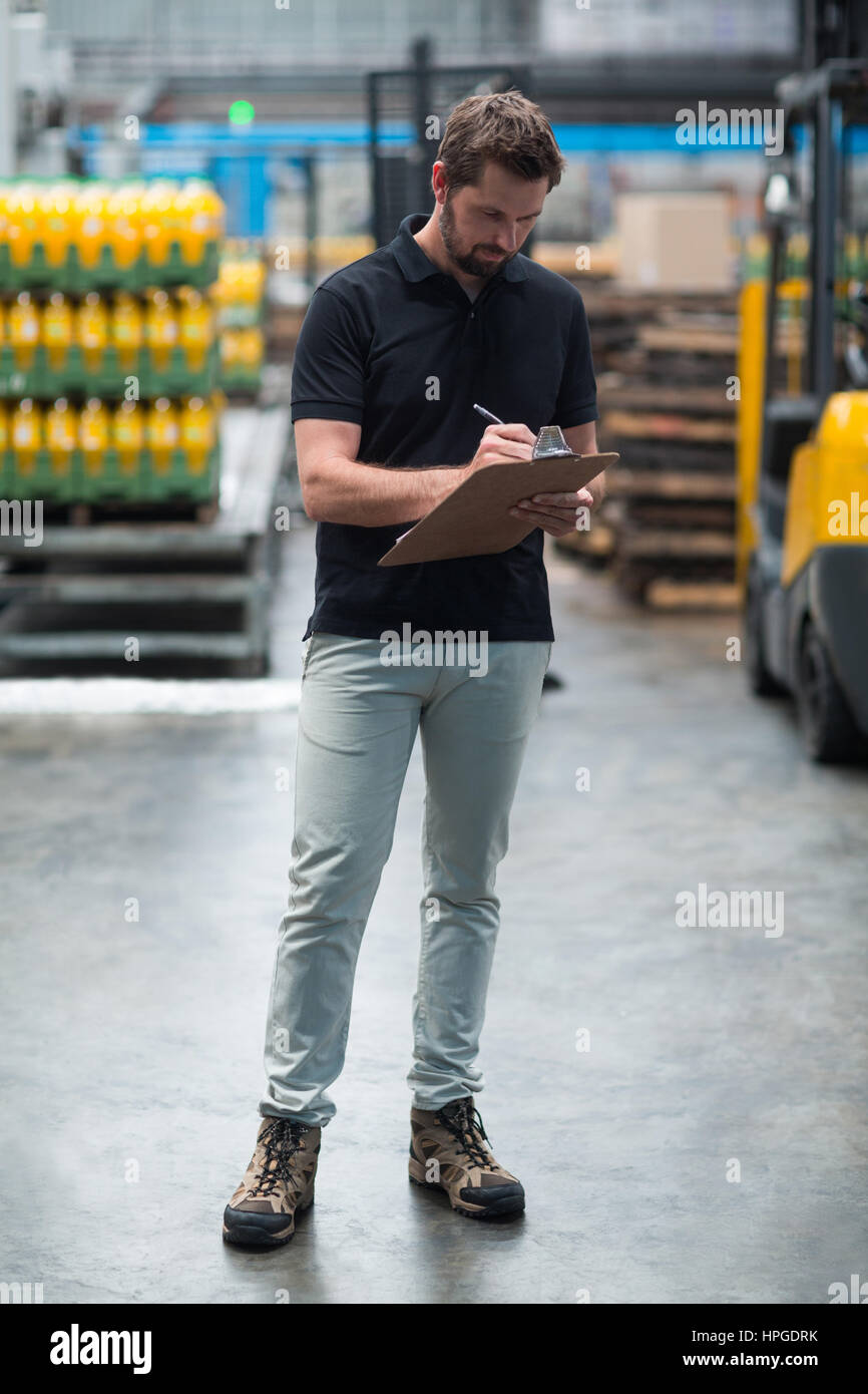 Factory staff writing on clipboard in factory Stock Photo - Alamy