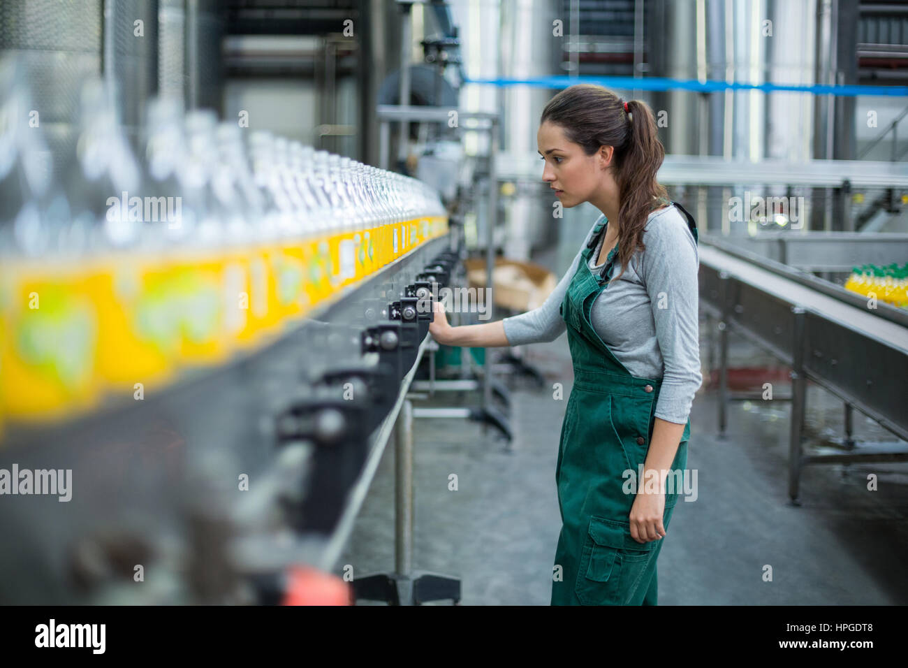 Female factory worker inspecting production line at drinks production ...
