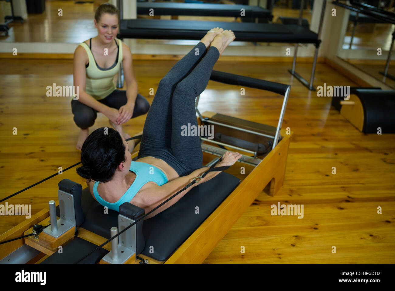 Female trainer assisting woman with stretching exercise in gym Stock ...