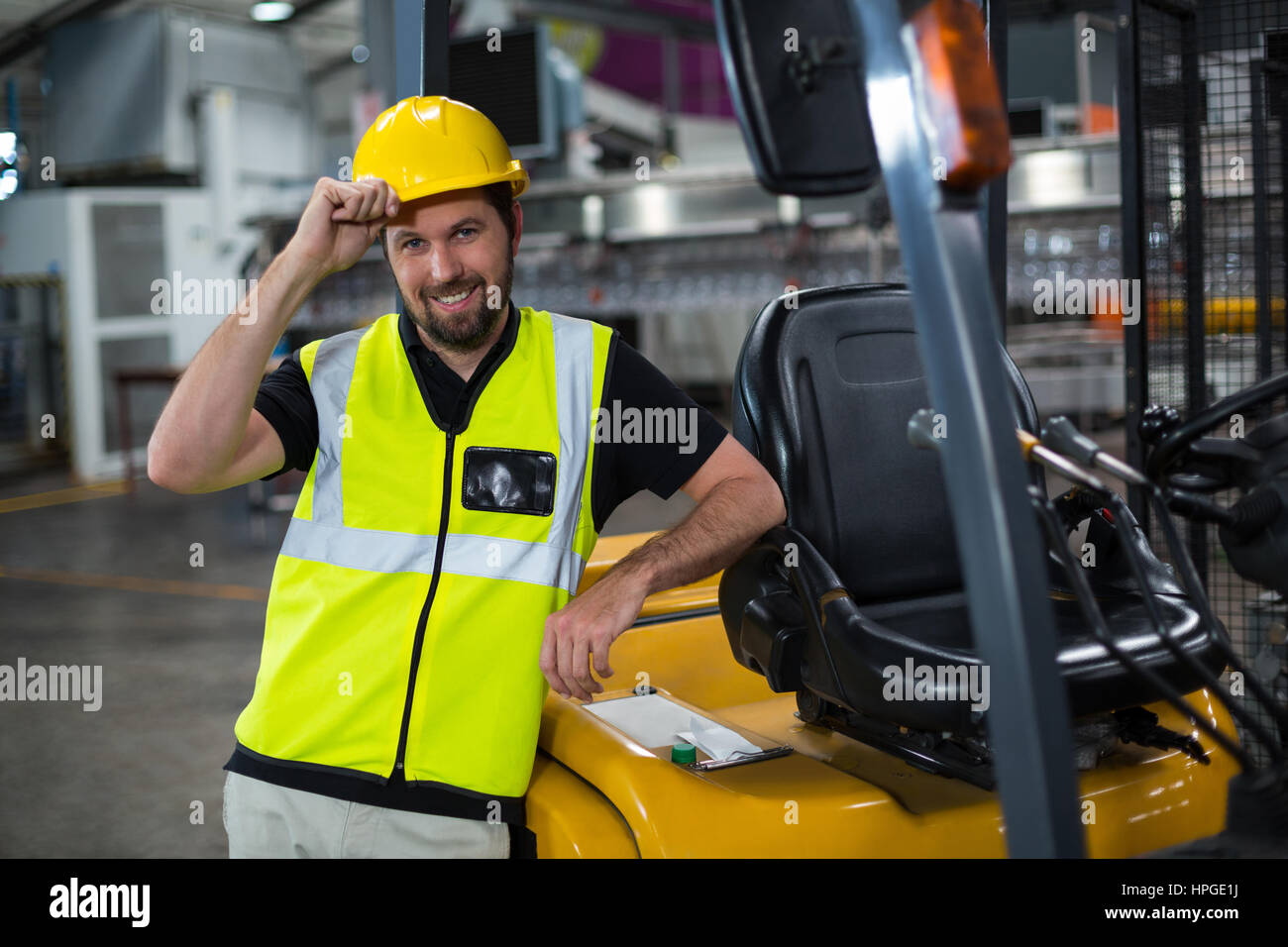 Portrait of smiling factory worker leaning on forklift in factory Stock ...