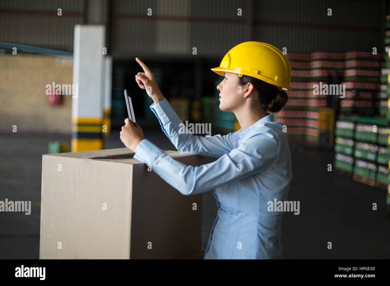 Attentive female factory worker maintaining record on mobile phone in ...