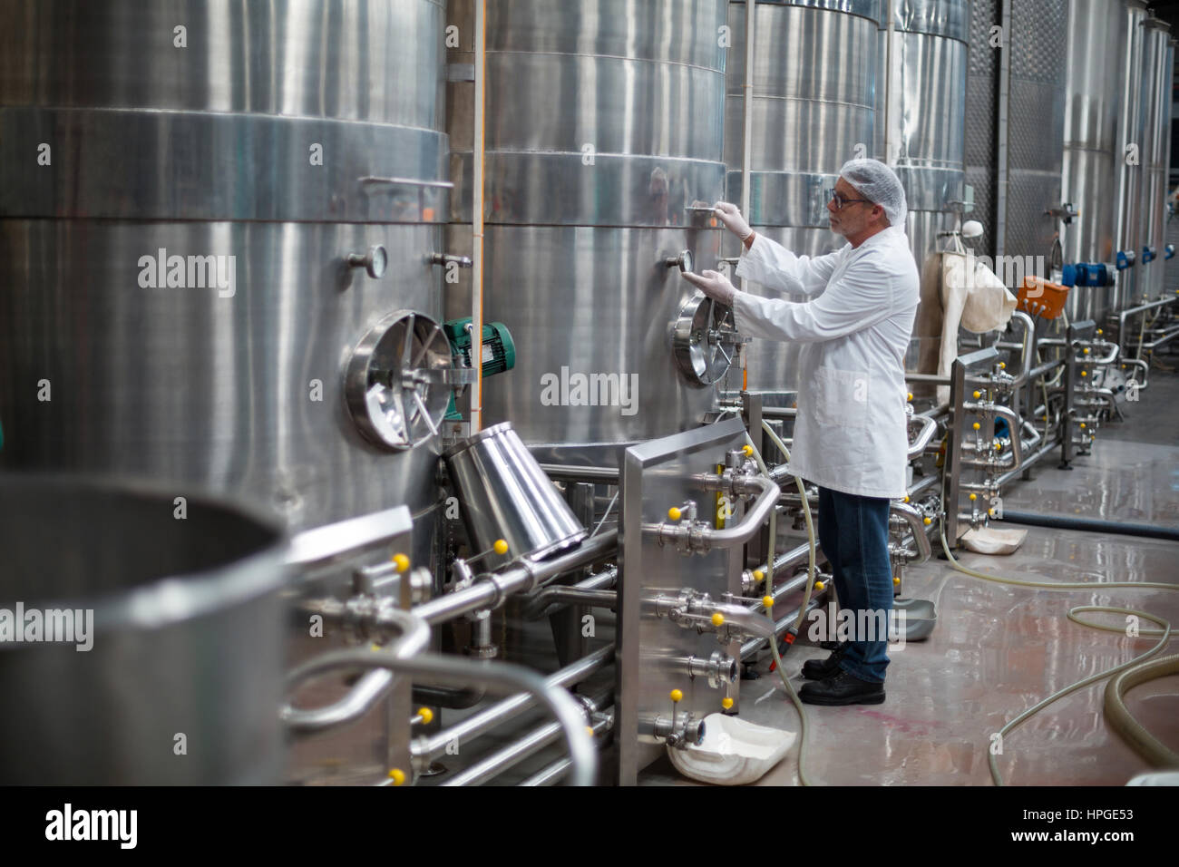 Factory engineer monitoring a pressure gauge of storage tank in bottle ...