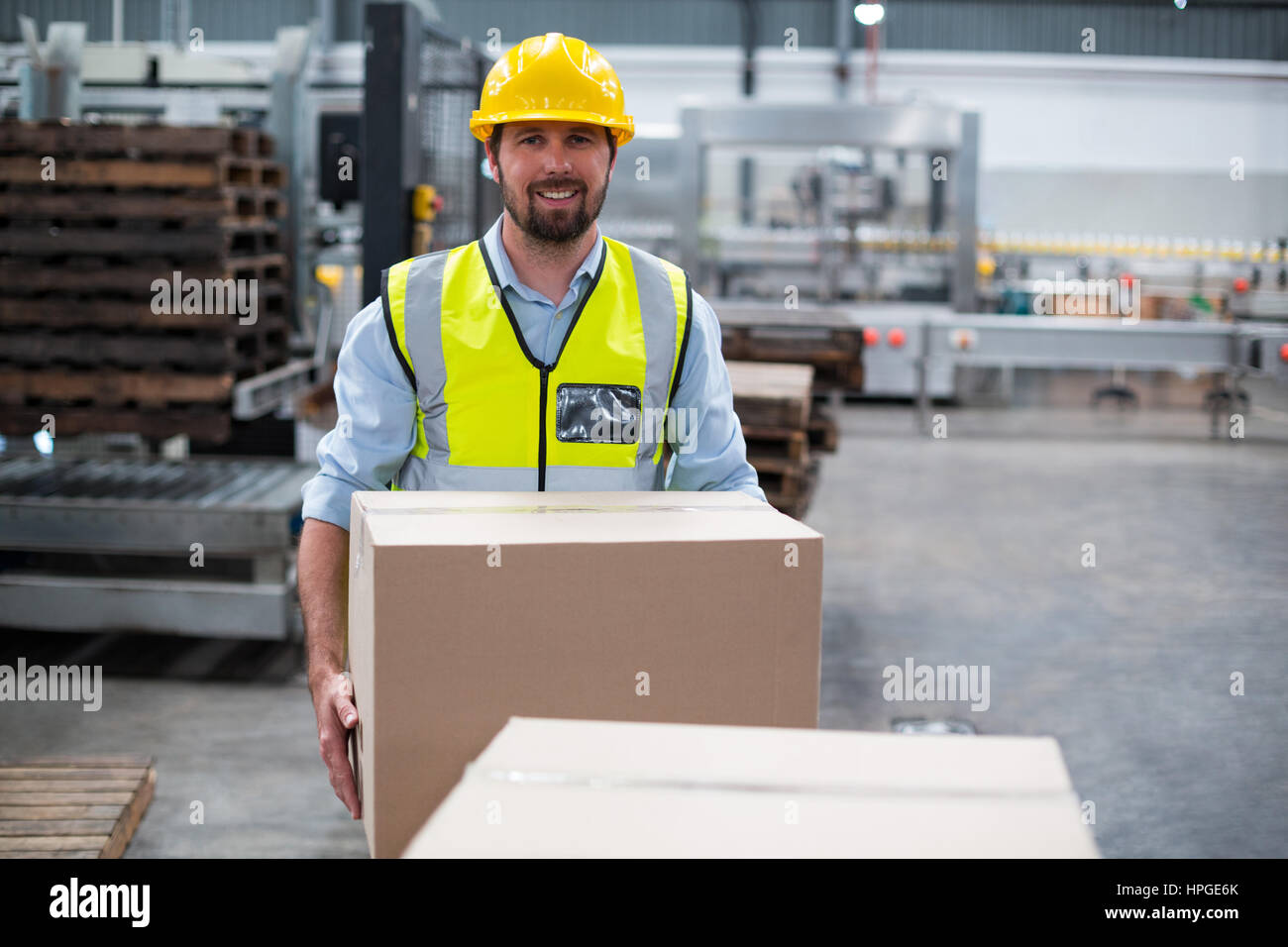Portrait of factory worker carrying cardboard boxes in factory Stock ...