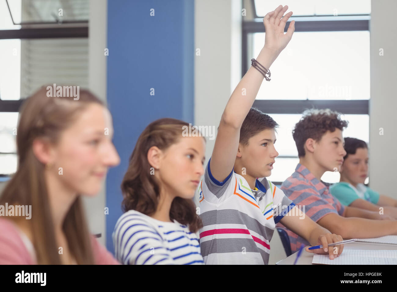 Student raising hand in classroom at school Stock Photo - Alamy