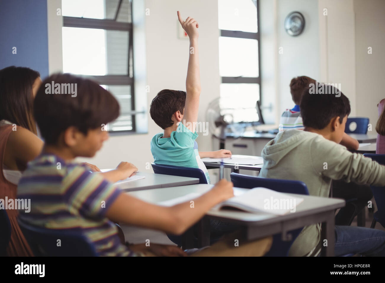 School kids raising hand in classroom at school Stock Photo - Alamy