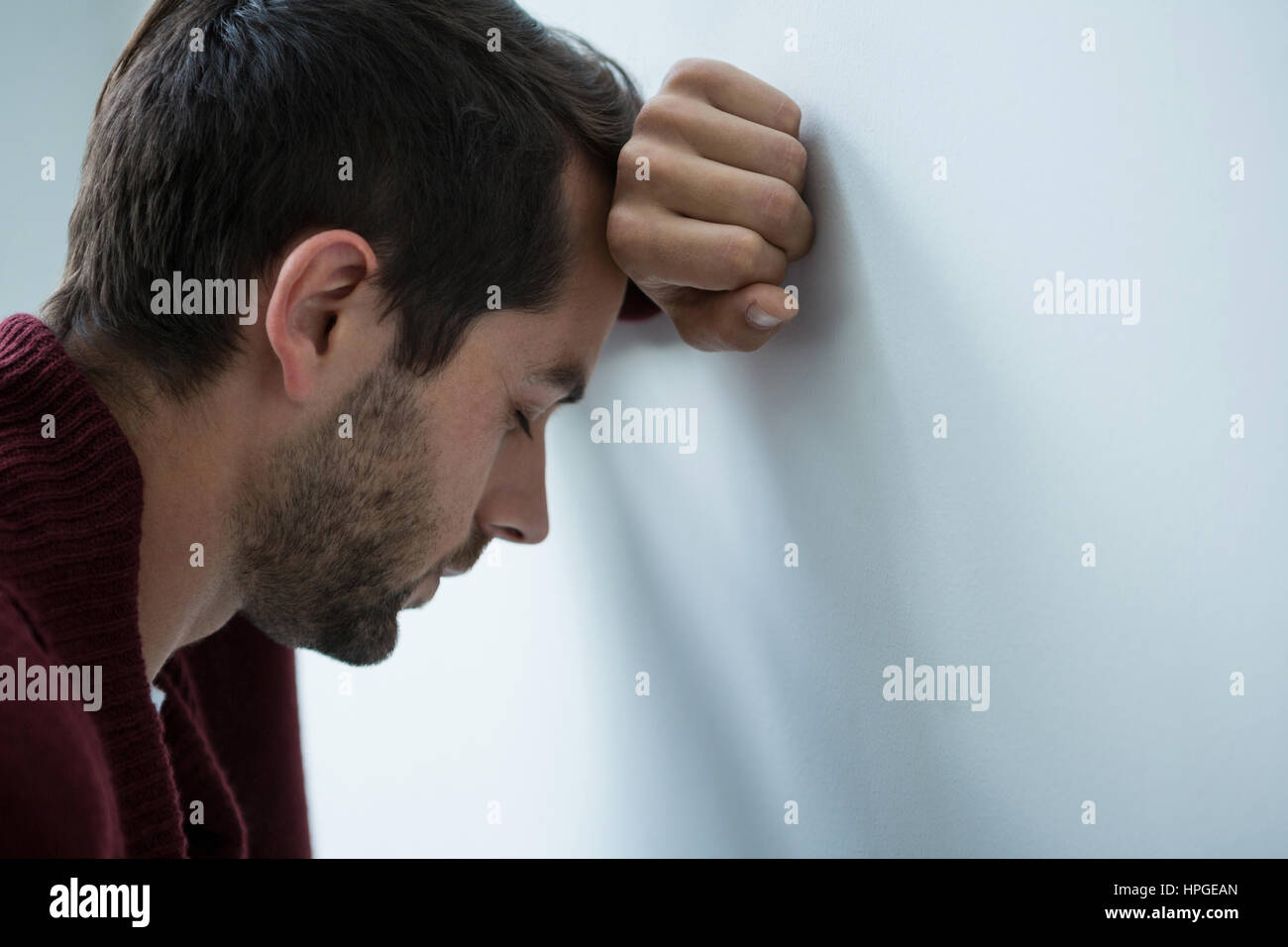 Close-up of a stressed man leaning on wall Stock Photo - Alamy