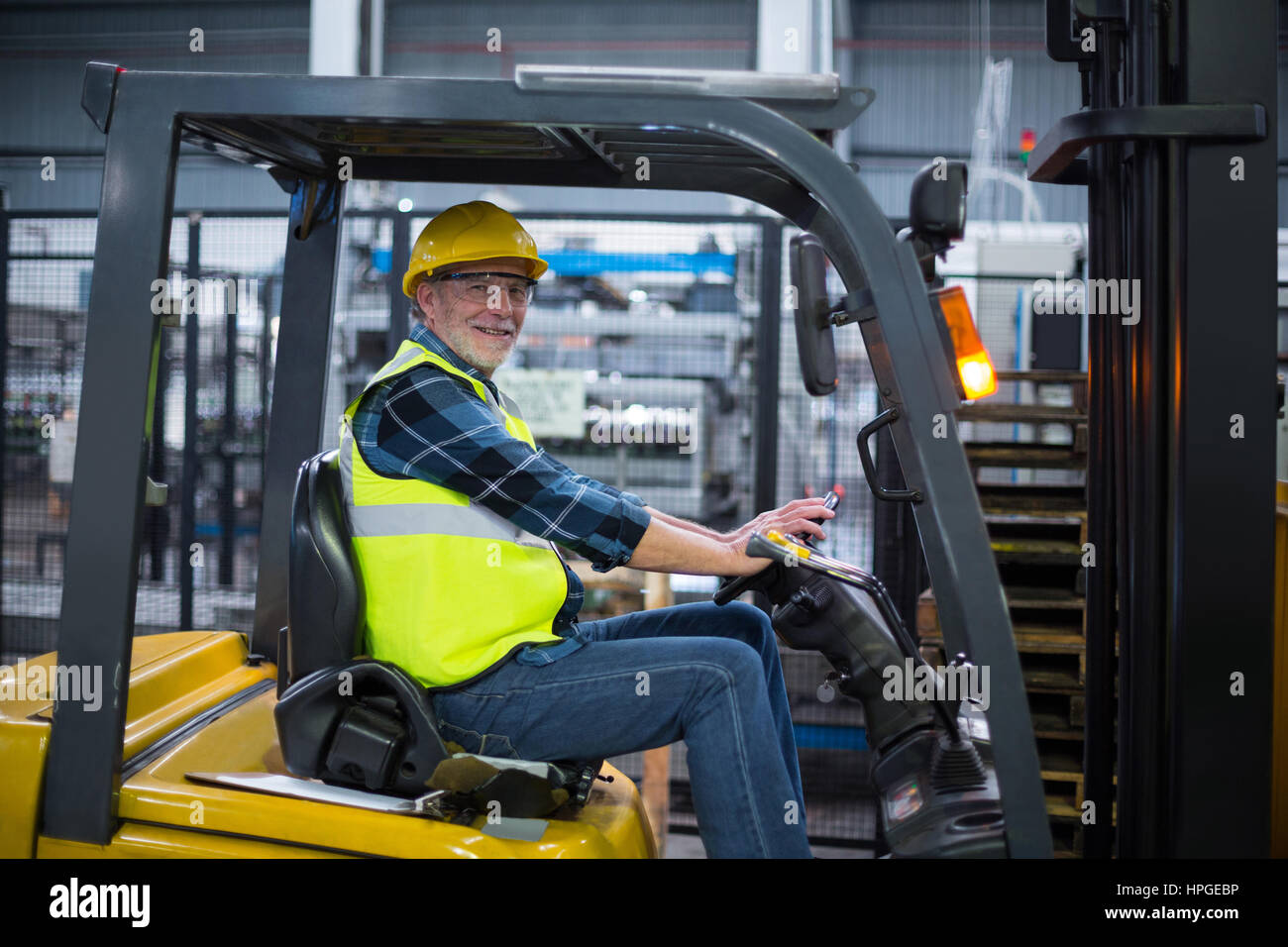 Portrait of smiling factory worker driving forklift in factory Stock ...