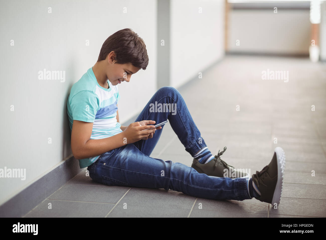 Happy schoolboy using mobile phone in corridor of school Stock Photo ...