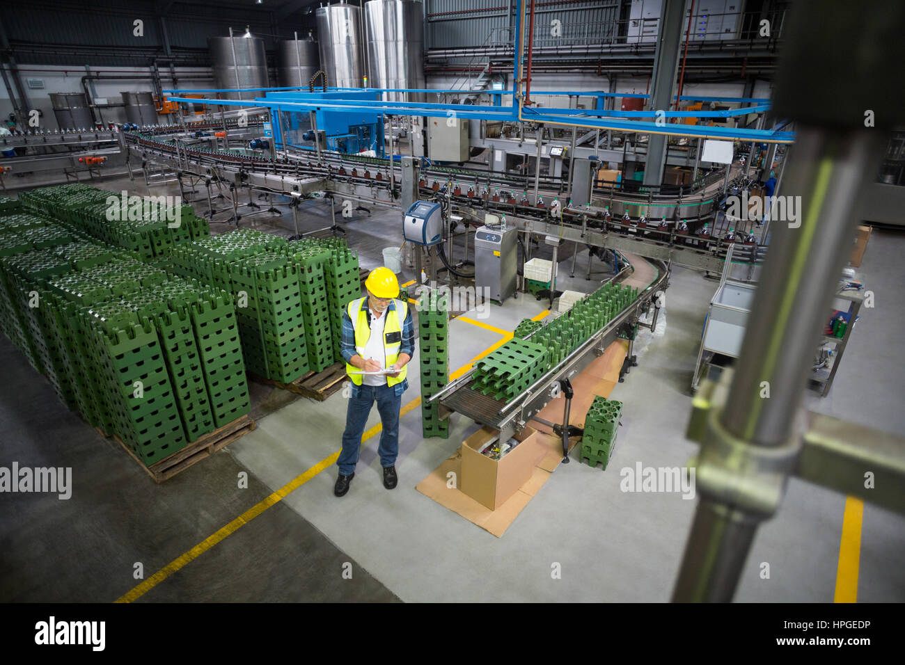 Male factory worker maintaining record on clipboard in drinks ...