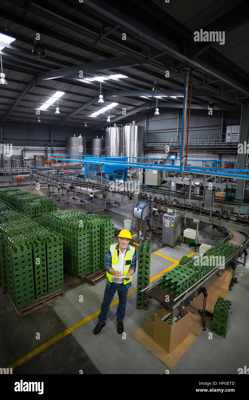 Male factory worker maintaining record on clipboard in drinks ...