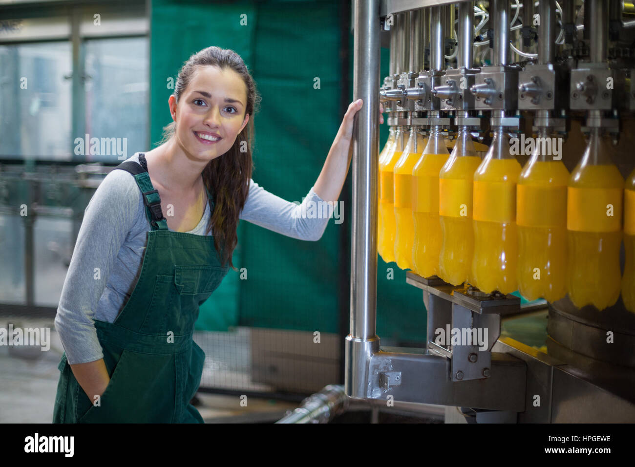Portrait of female factory worker standing near production line at ...